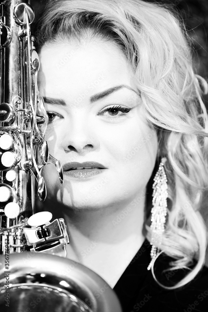 Portrait of a charming blonde with a saxophone in her hands. Beautiful ...