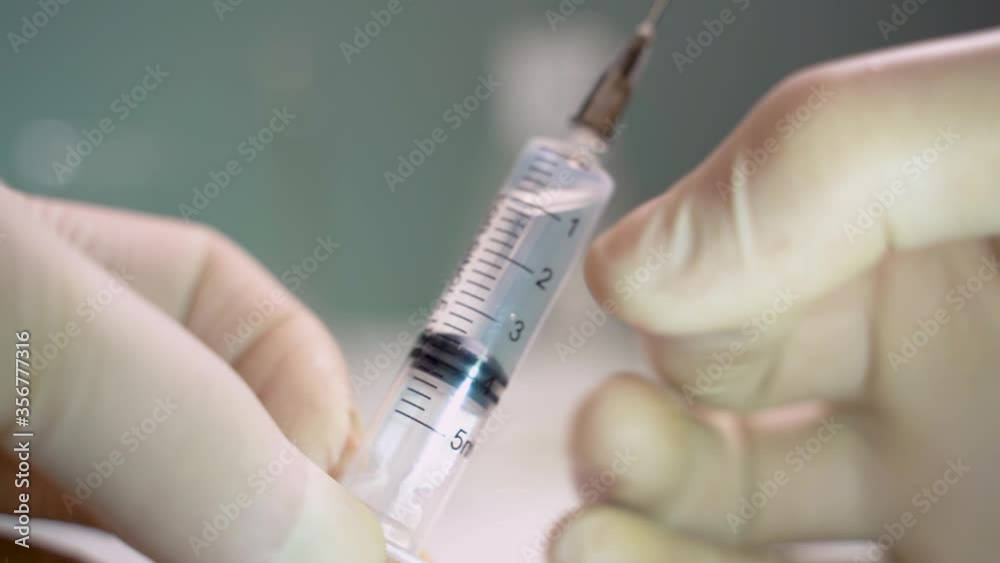 Medical worker taps on a syringe. Removing air from a syringe before ...