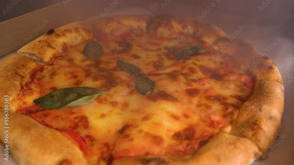 Opening box with pizza with a steam. Fresh pizza is in the box with ...
