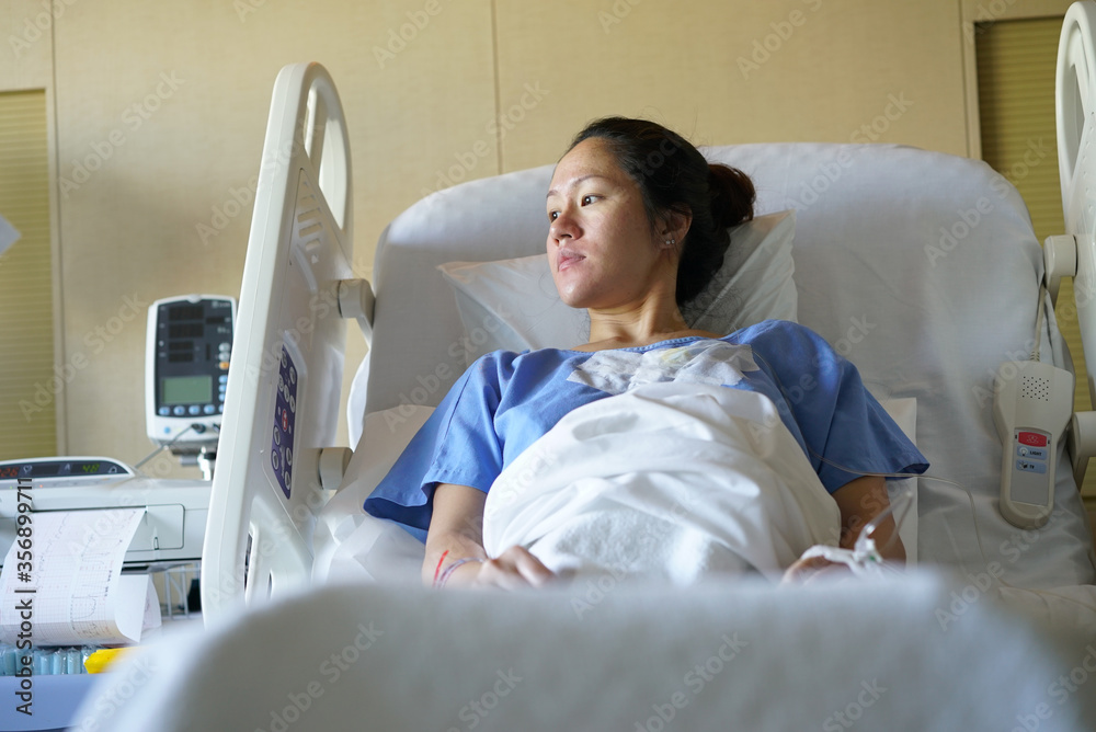 Asian chinese woman patient lying in hospital ward and looking out of ...