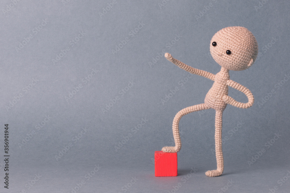 A toy man on a gray background with space for text. Knitted toy ...