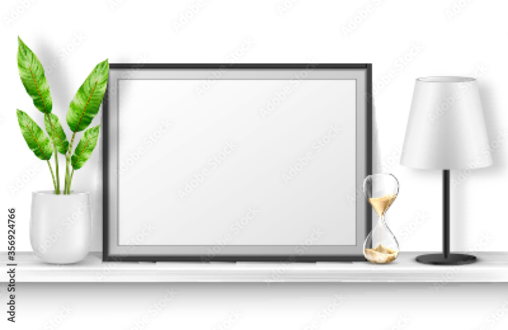 Empty photo frame stand on white shelf with potted plant, hourglass and ...