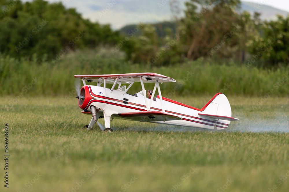 R/C biplane airplane taking off the grass with smoke behind Stock Photo ...