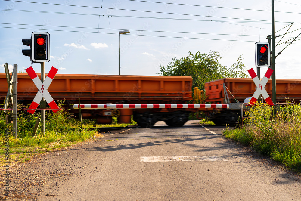 Closed barrier at the railroad crossing with red warning lights on ...