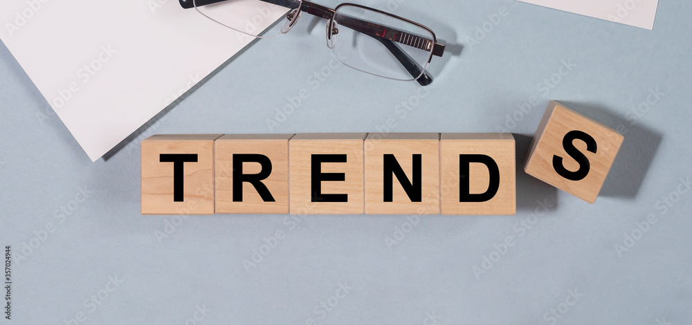 Word TRENDS on cube blocks on a blue grey table with glasses and ...