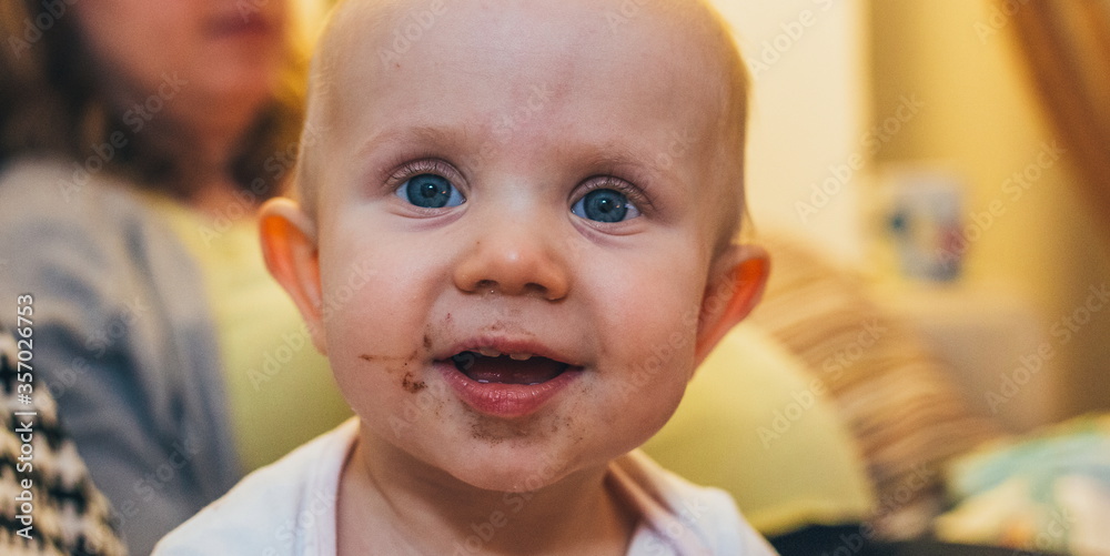 Small girl with chocolate smeared all over her face. Funny faces with ...