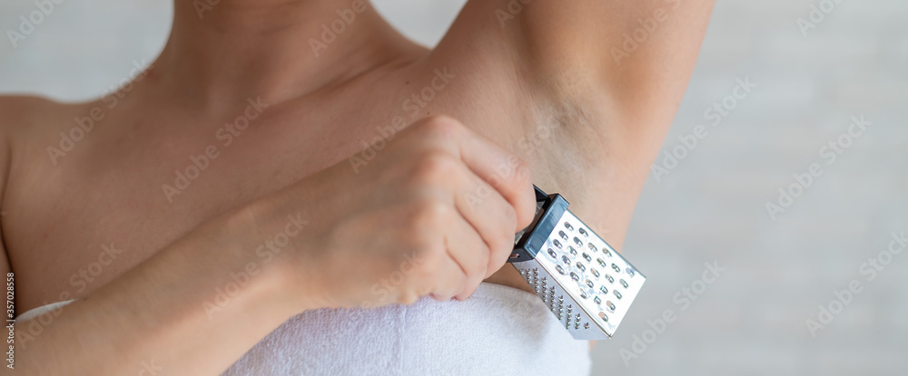 Unrecognizable woman in a white terry towel holds a mini grater ...