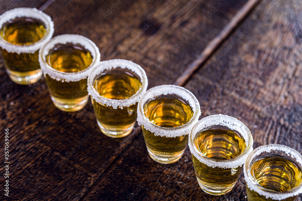 tequila glasses lined up, with tequila, lemon and salt. typical drink ...