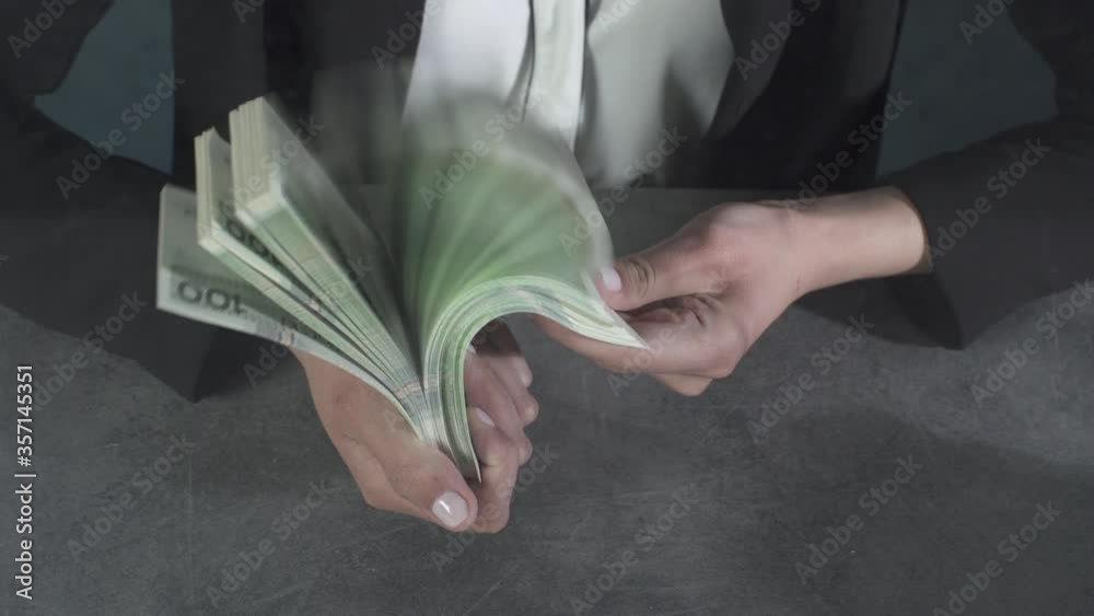 The banker hands new banknotes with her hands. The woman shuffles money ...