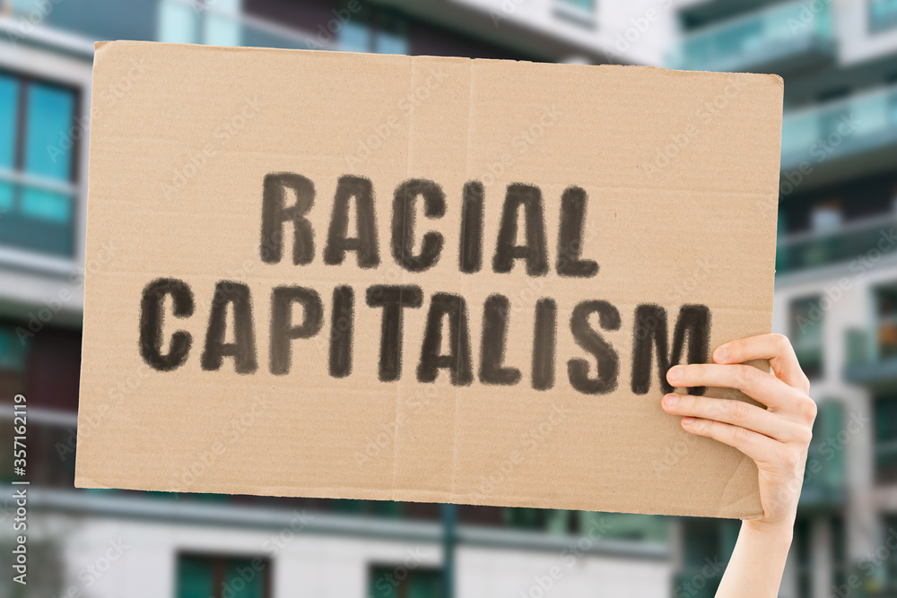 The phrase " Racial capitalism " on a banner in men's hand with blurred ...