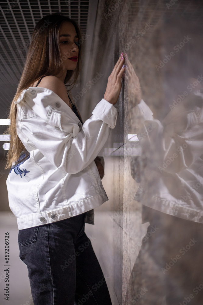 A teenage girl stands facing the wall holding her hand in her ...