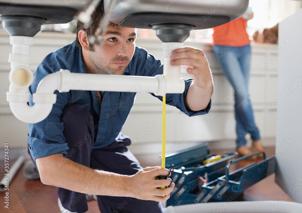 Plumber working on pipes under kitchen sink Stock Photo | Adobe Stock