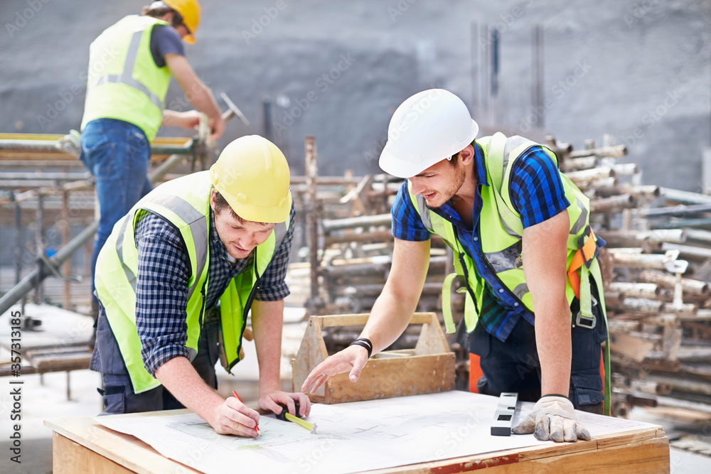 Construction worker engineer revising blueprints at construction site ...