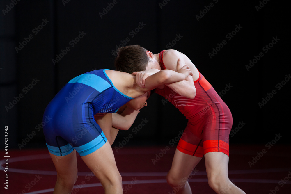 Wrestlers in red and blue singlets practicing on a red mat. Stock Photo ...