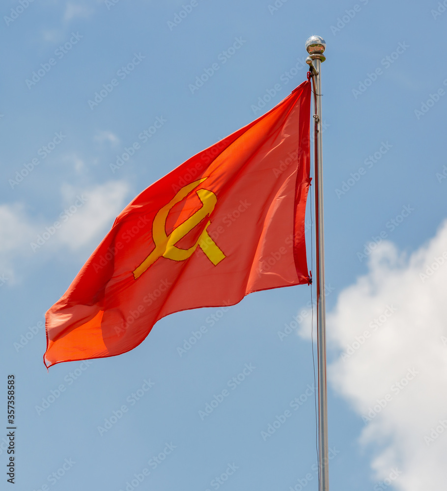 A red flag with communist symbols of a sickle with a hammer flying in a ...