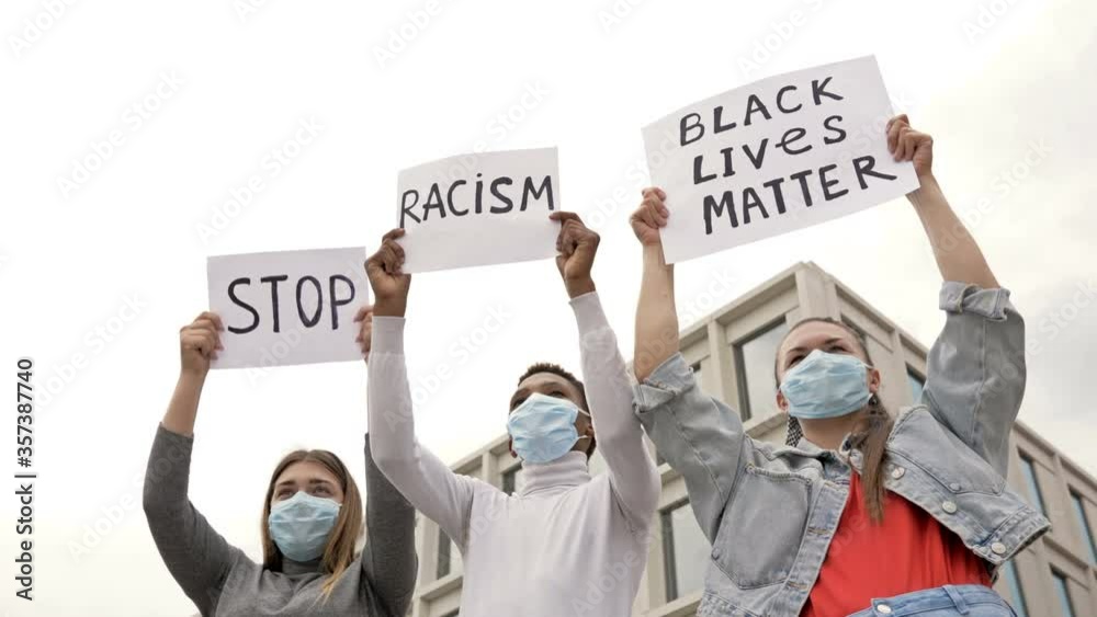 Three young people in a medical masks protest against racial inequality ...