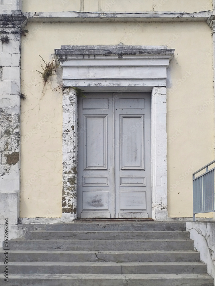 Stairs and old colonial facade with gray door with worn white stone ...