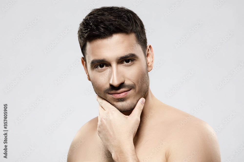 Portrait of young handsome guy not wearing shirt, touching his chin ...
