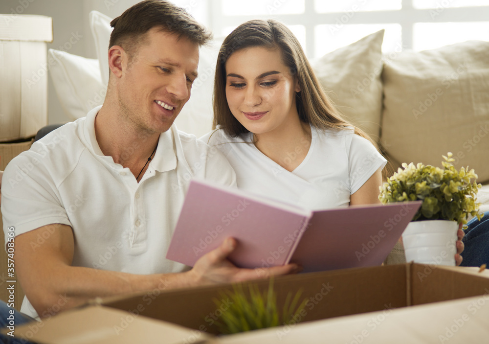 Cute couple unpacking cardboard boxes in their new home, sitting on the ...