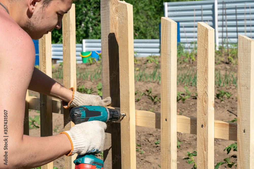 Building a wooden fence with a screwdriver. Natural eco-friendly ...