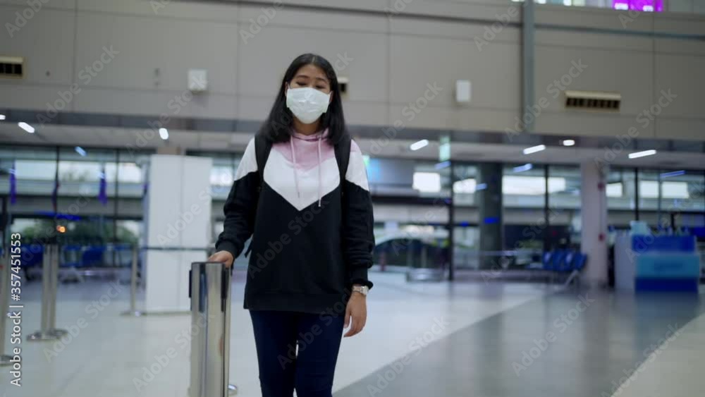 Vidéo Stock Young Asian female wear medical mask walking slowly alone at airport terminal ...