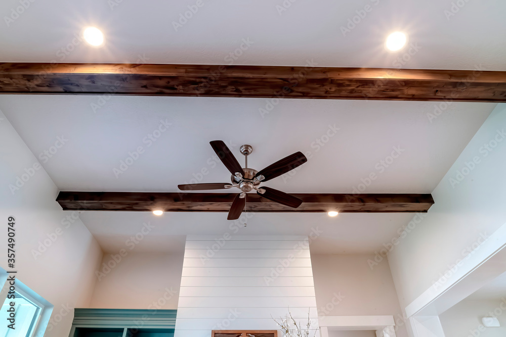 Ceiling fan with lights between decorative wood beams inside living ...