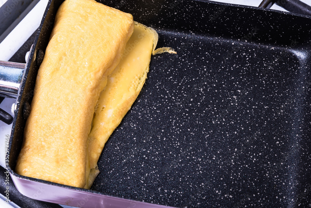 Foto de Cooking tamago Japanese omelet in a special pan for tamagoyaki ...