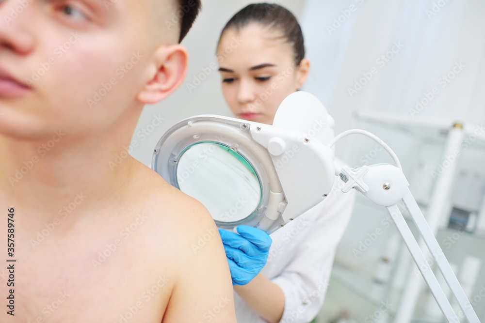 doctor dermatologist-a young woman examines the skin condition of a ...