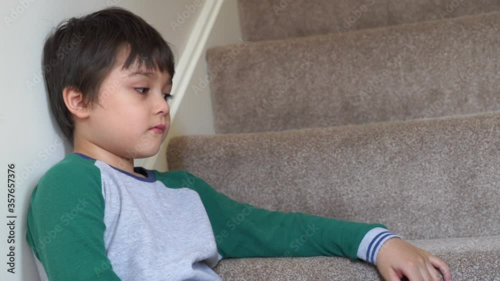 Kid boy with sad face sitting on stair case, Sad child looking down ...