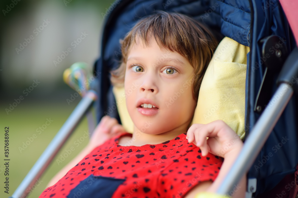 Portrait of a cute little disabled girl in a wheelchair. Child cerebral ...