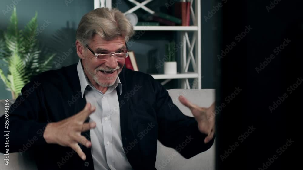 Vidéo Stock An elderly grey-haired man is watching TV and cheering ...