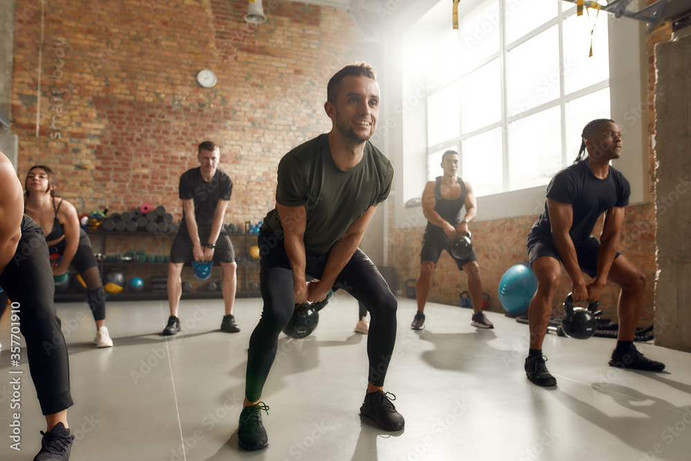 Come to be healthy. Group of sportive people lifting weight while ...
