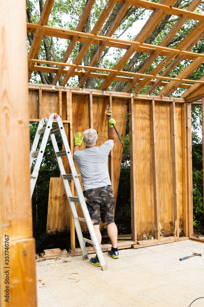 Demolition phase with a man tearing down an old shed with a crowbar in ...