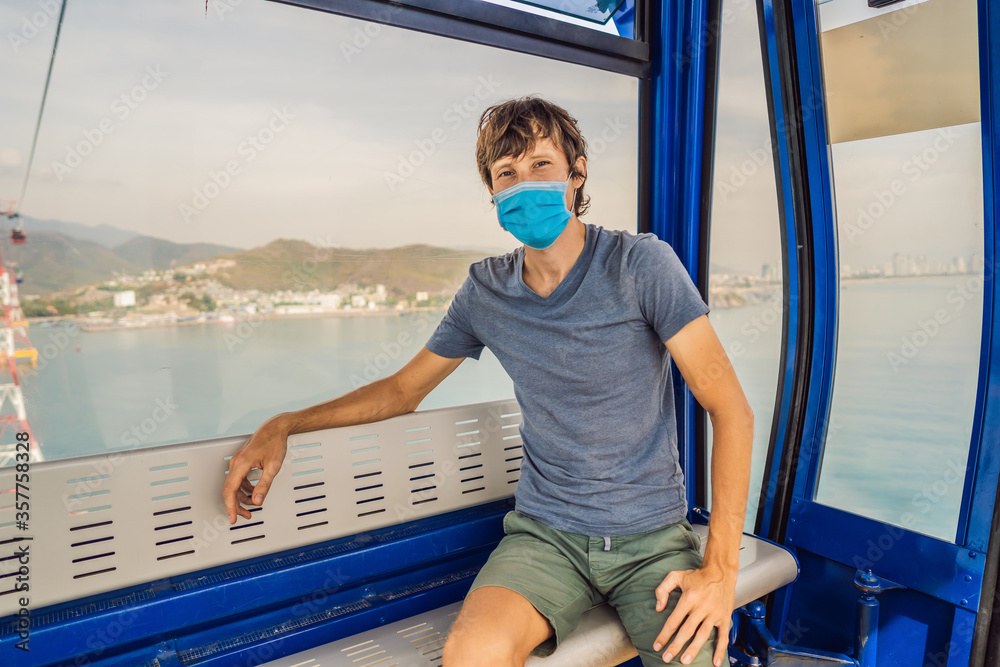 Man wearing a hygiene protective mask over face while ride a cable car ...
