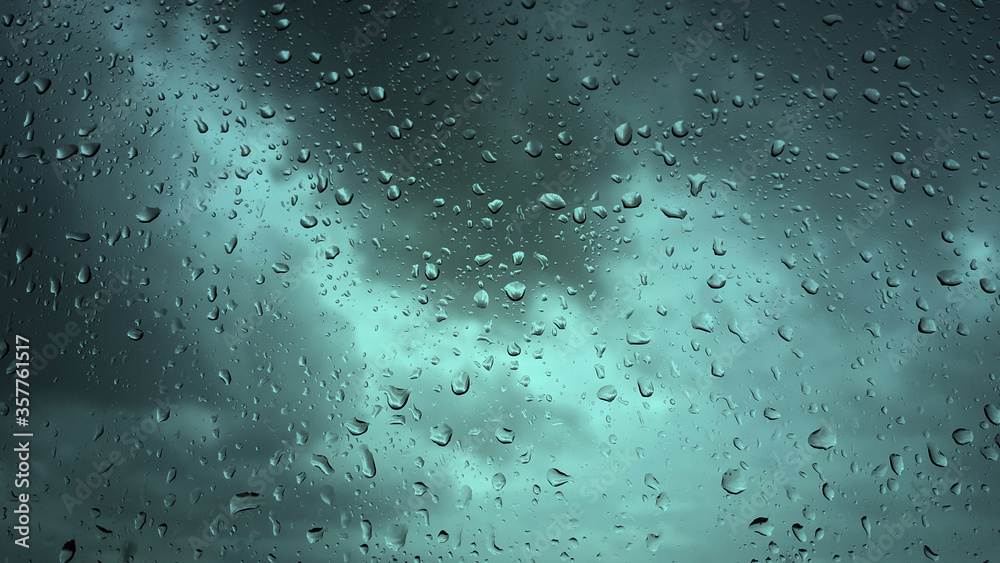 Raindrops on transparent glass window. Heavy rain storm over dark blue ...