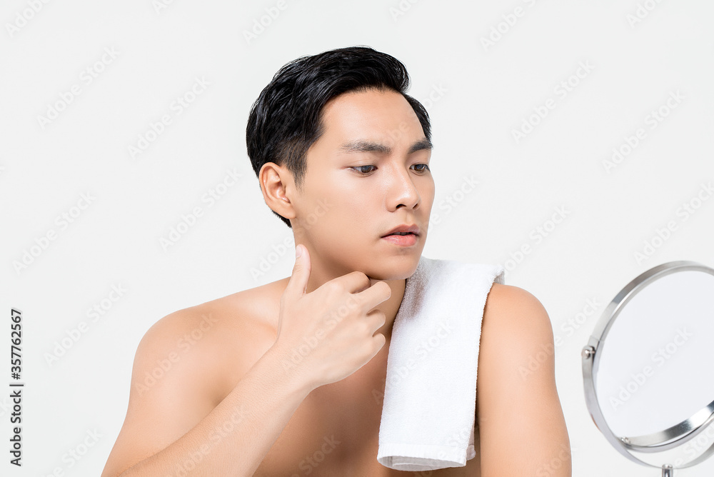 Shirtless young handsome Asian man looking at his face in the mirror ...