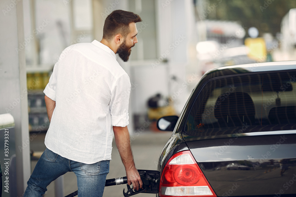 Man on a gas station. Guy refuelong a car. Male in a white shirt. Stock ...