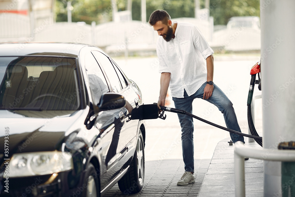 Man on a gas station. Guy refuelong a car. Male in a white shirt. Stock ...