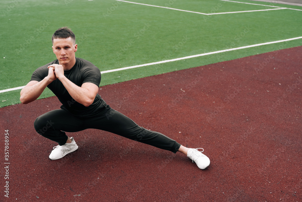 The athlete makes lunges, exercise to warm up before training. Male ...