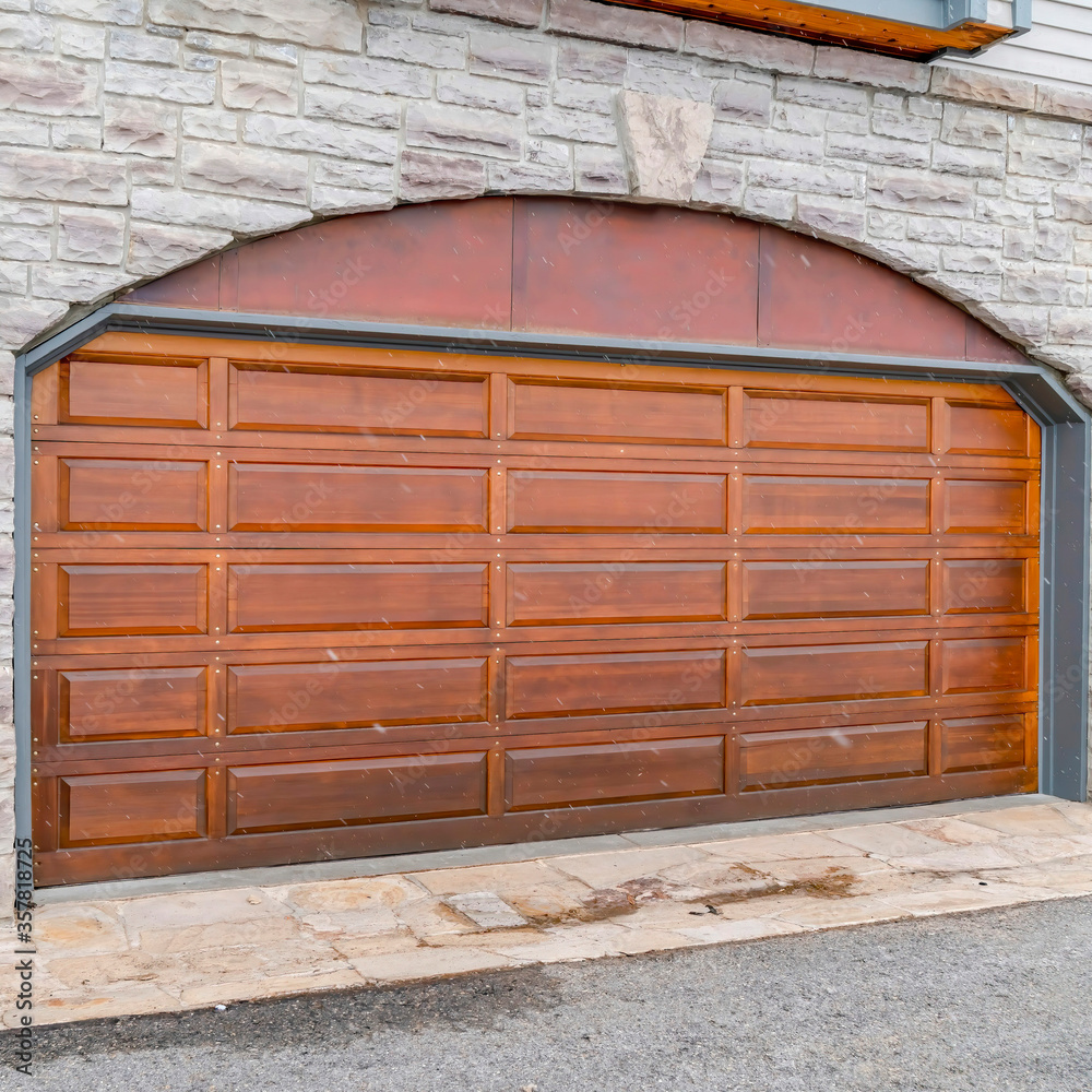 Square frame Arched brown wood panel garage door of home with stone ...
