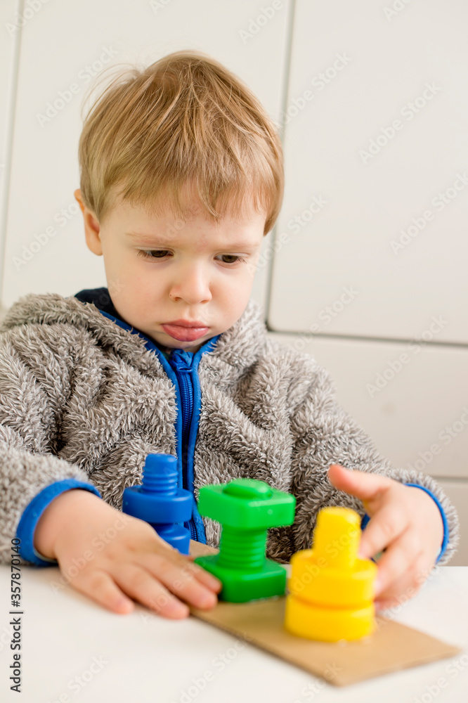 Shapes, colors and fine motor skills. Toddler turns the nut on the bolt ...