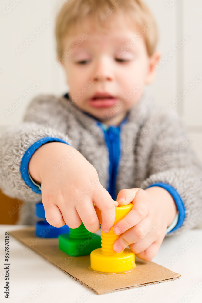 Shapes, colors and fine motor skills. Toddler turns the nut on the bolt ...
