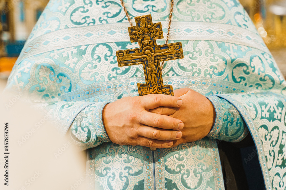 Holy father in his robe with a golden cross in his hands in church ...