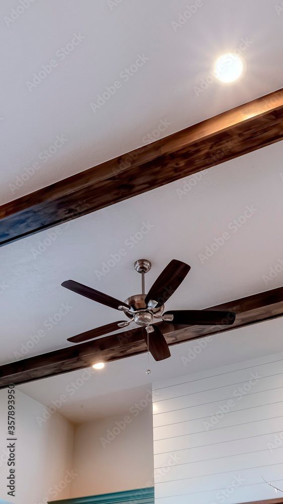 Vertical Ceiling fan with lights flanked by decorative wood beams and ...