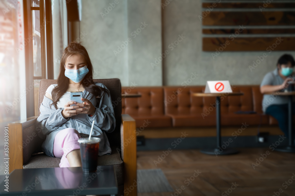 Social distancing concept.Young asian woman in facial mask sitting use ...