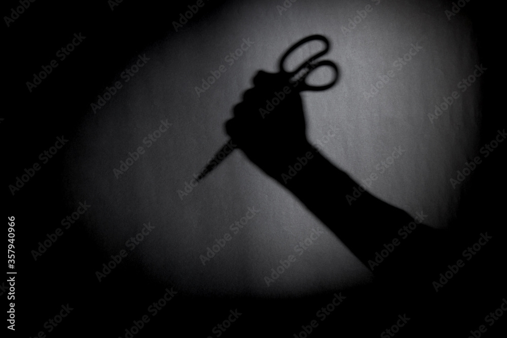 man with scissors silhouette over dark wall. black and white photo can ...