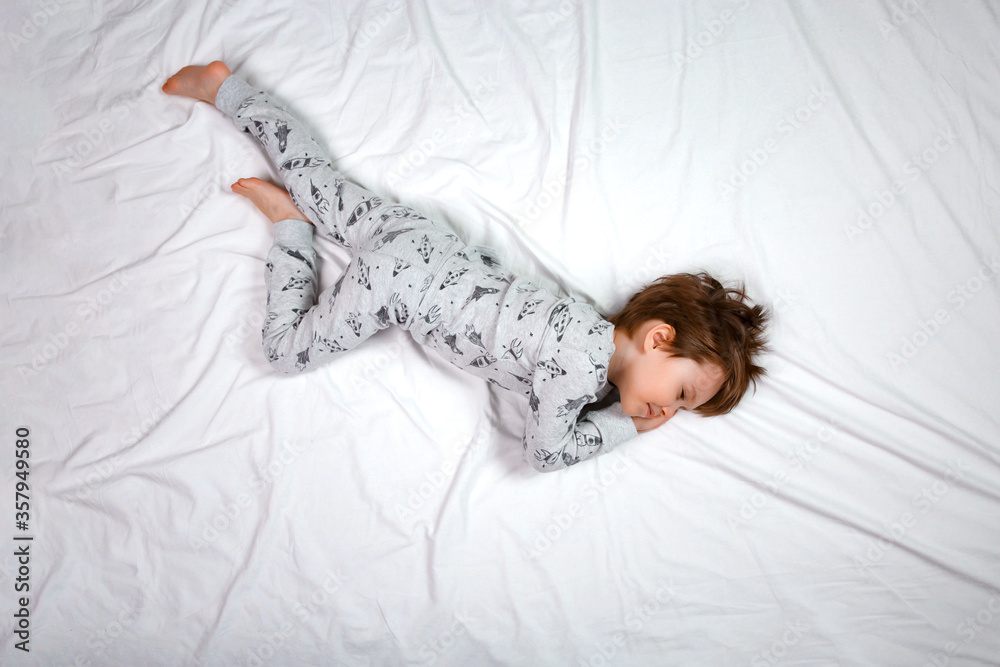From above a boy is seen sleeping on a white bed in pajamas. Calm ...