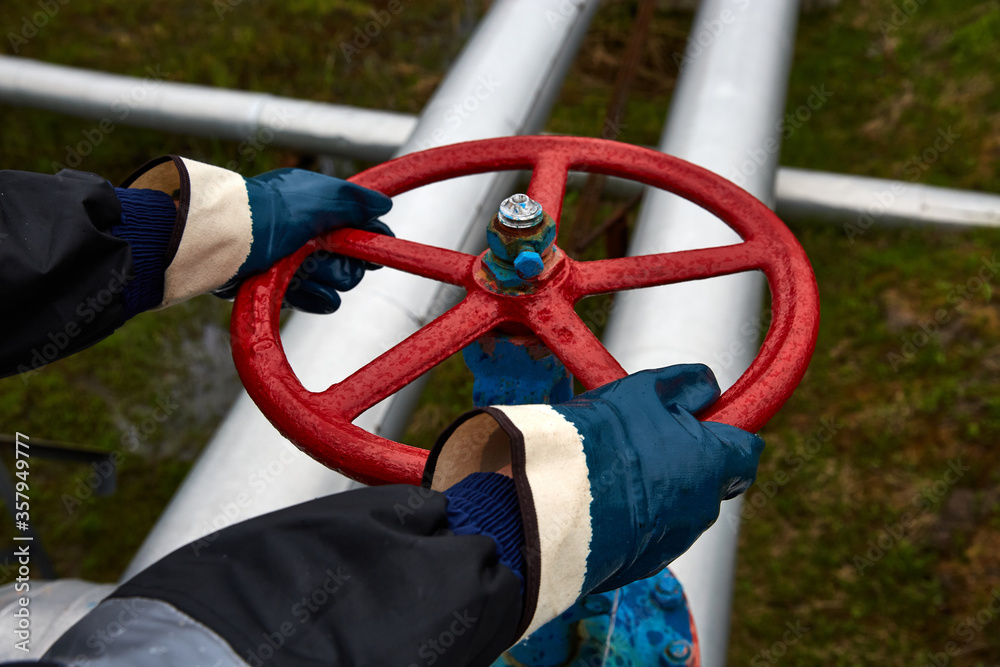 Worker turns the valve and closes the oil supply. Hands and stop valves ...