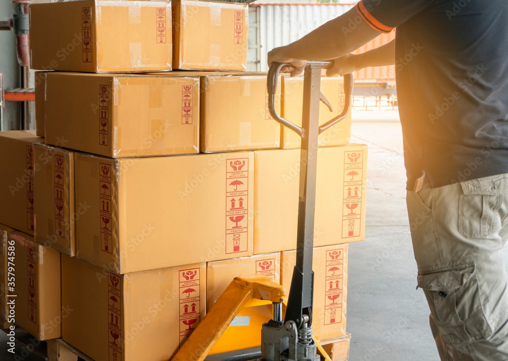 Worker courier unloading shipment boxes. Hand pallet truck and stack ...