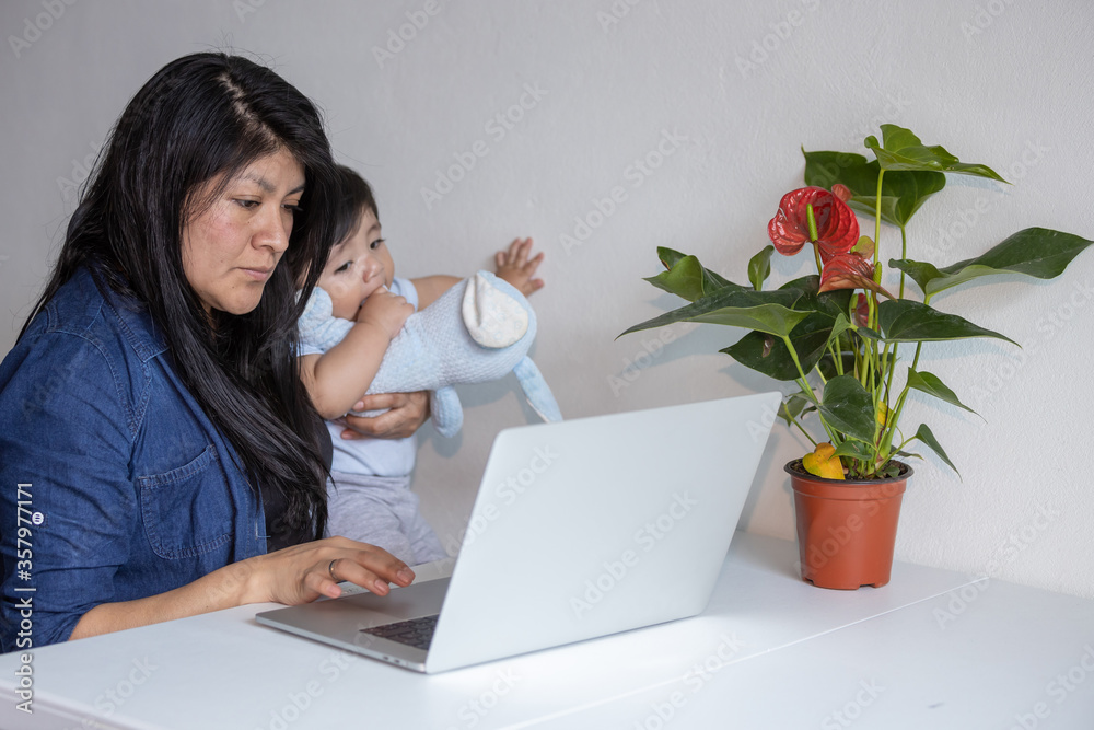 Mexican Mother working from home while her son distracts her and ...